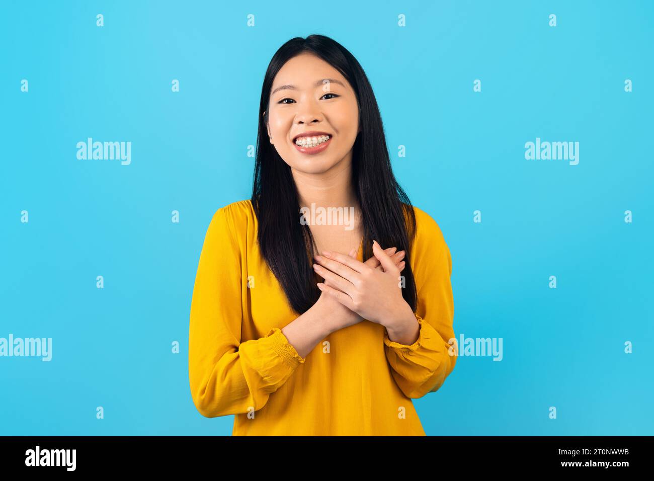 Positive thankful young korean woman holding hands over heart Stock ...