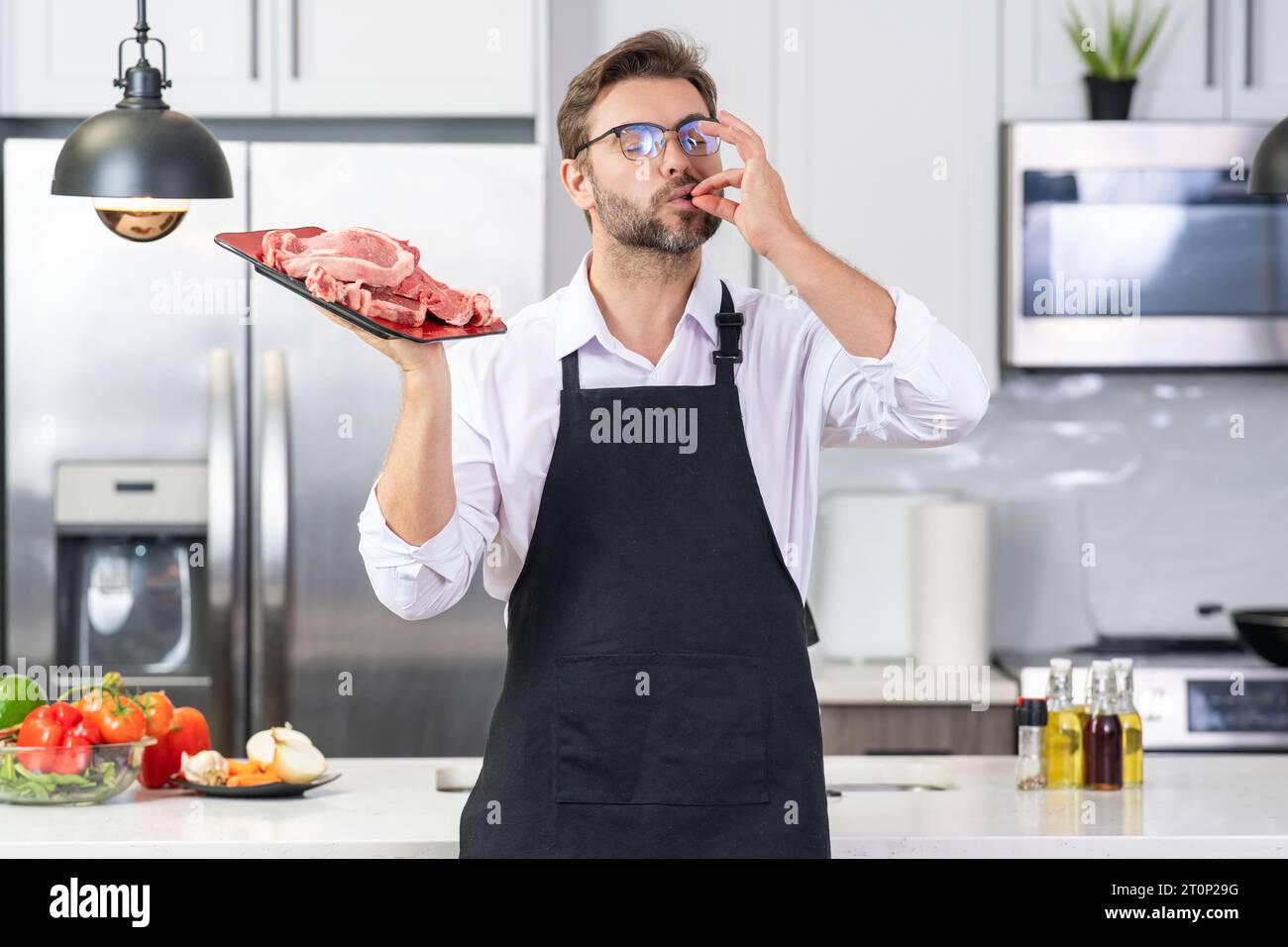 Chef with raw meat beef fillet on kitchen. Handsome man chef cooking ...