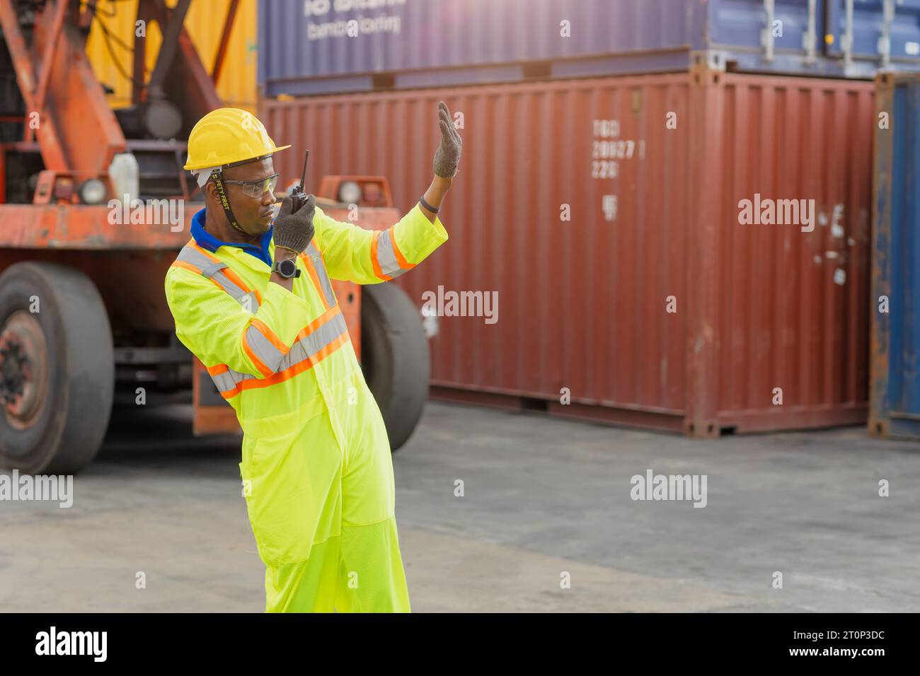 African male dock worker control loading containers cargo at warehouse ...