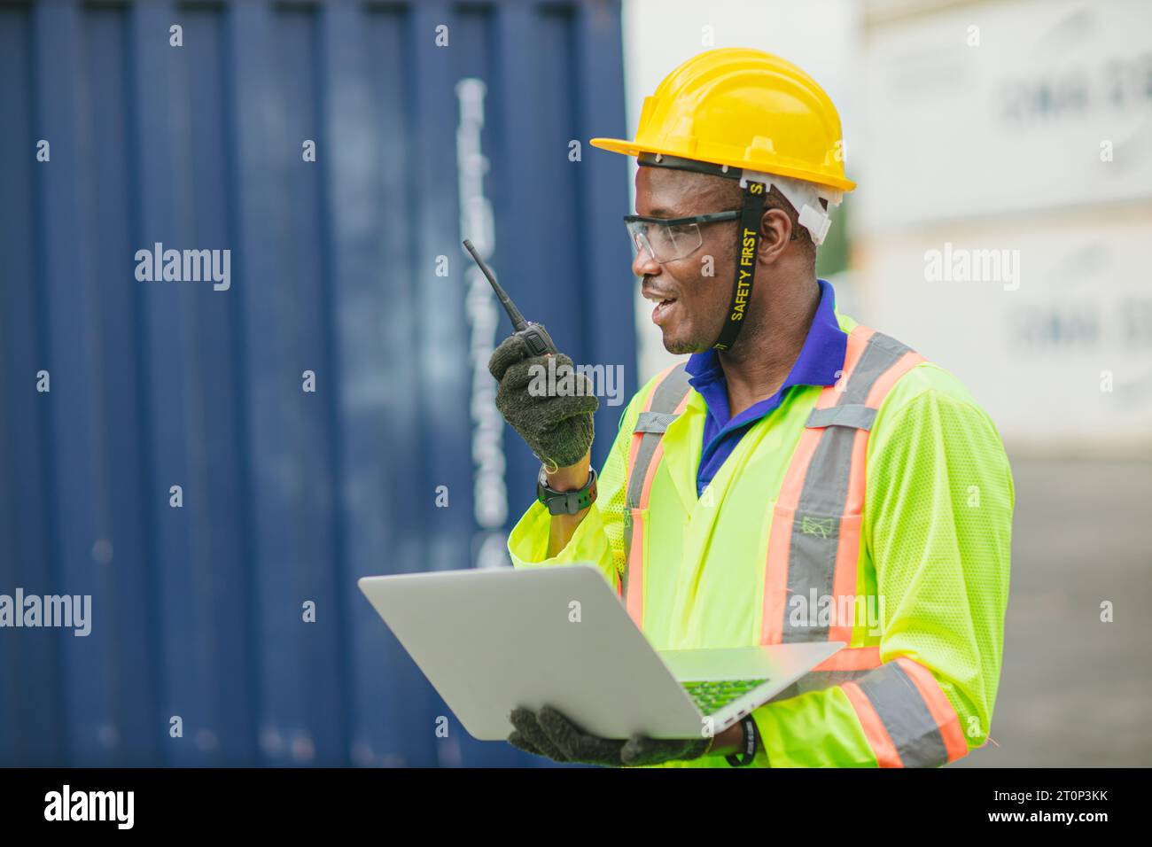 African male dock worker control loading containers cargo at warehouse ...
