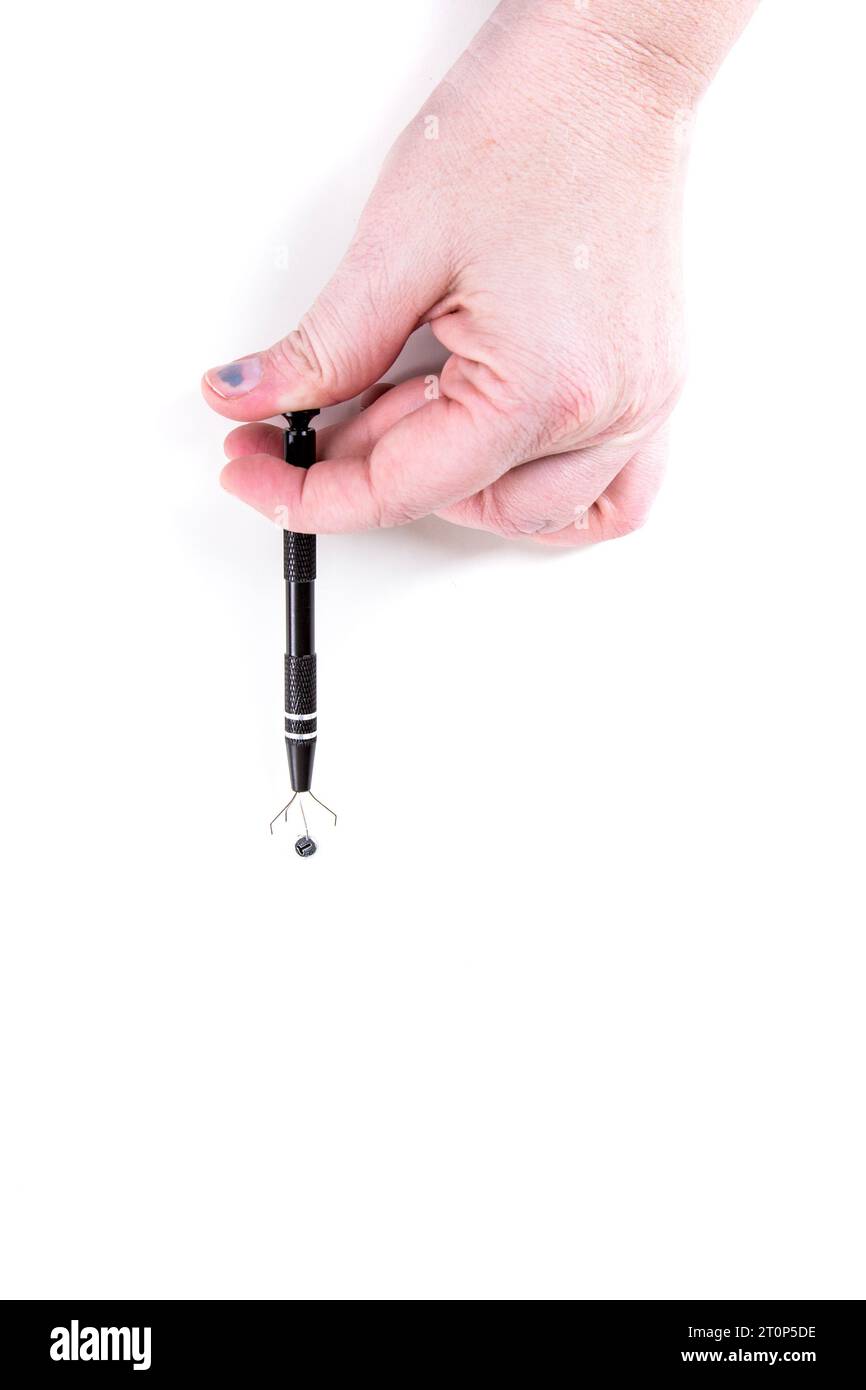 Human hand grasping a bead with a wire grabber tool Stock Photo - Alamy