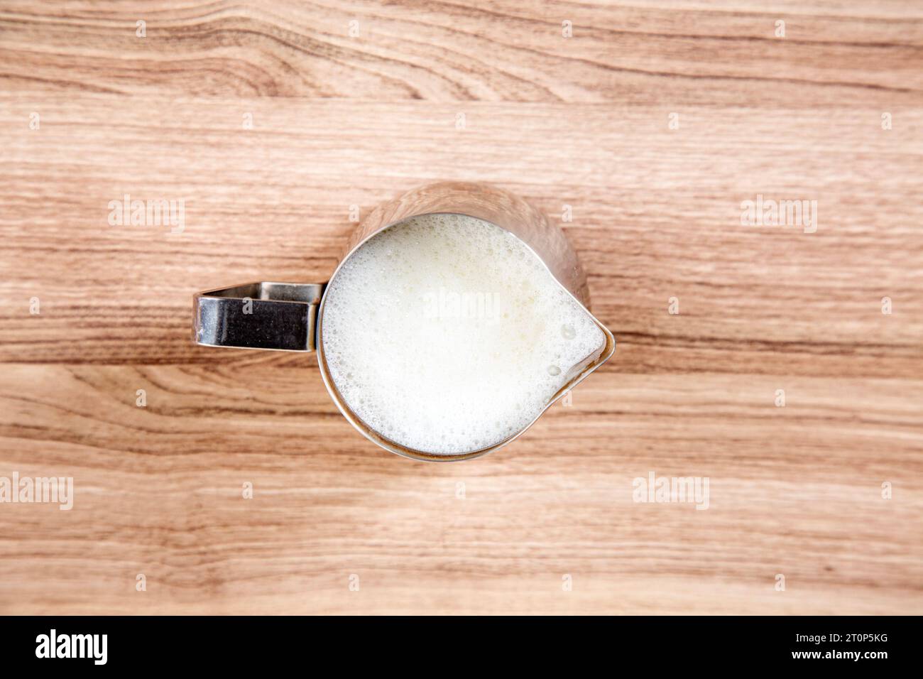 Steamed milk in a silver cup top down view Stock Photo - Alamy