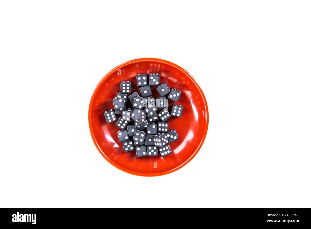 Tiny black and white dice pile in a red bowl isolated over white top ...