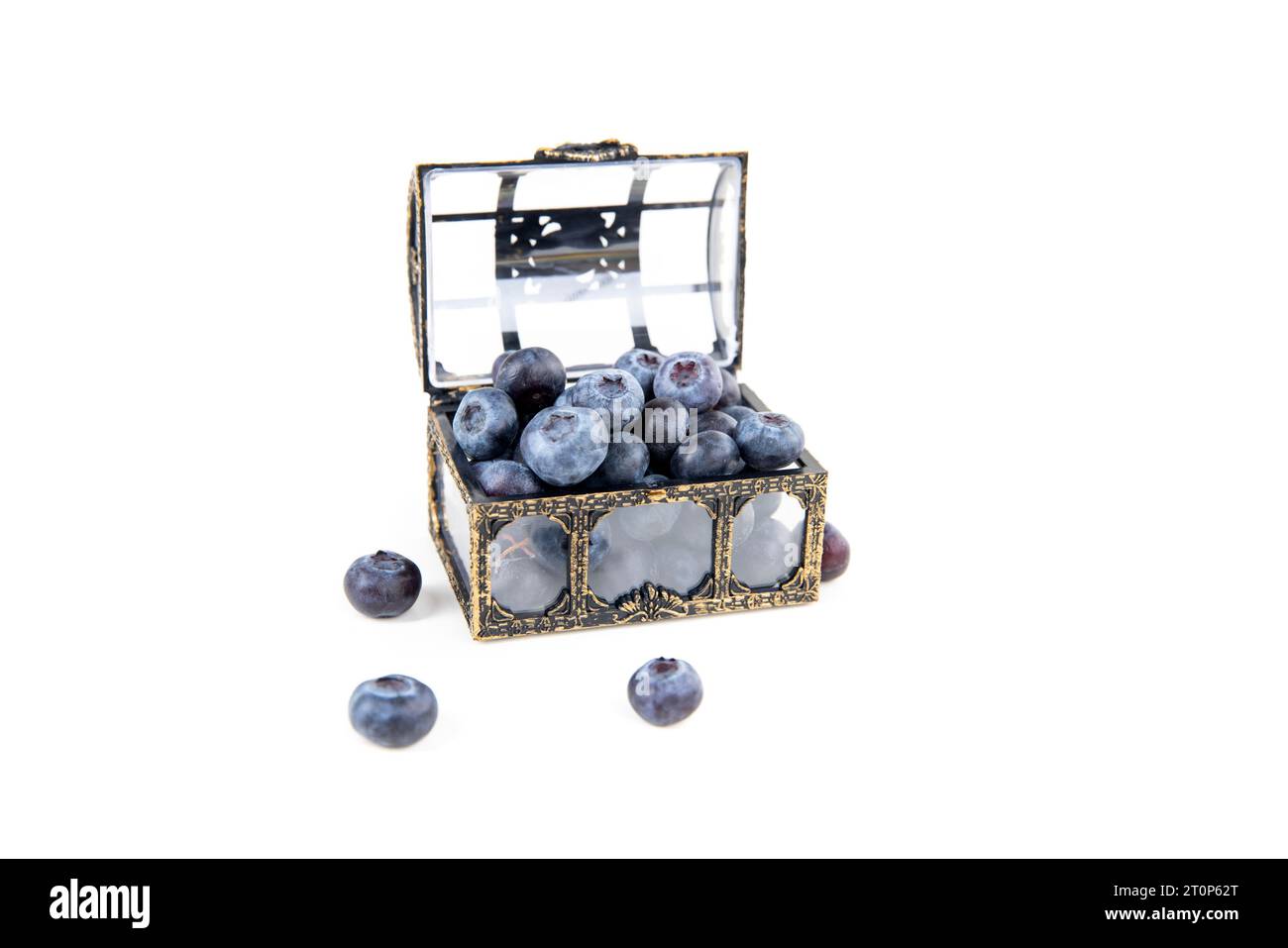 Small gold and glass treasure chest open and filled with blueberries ...