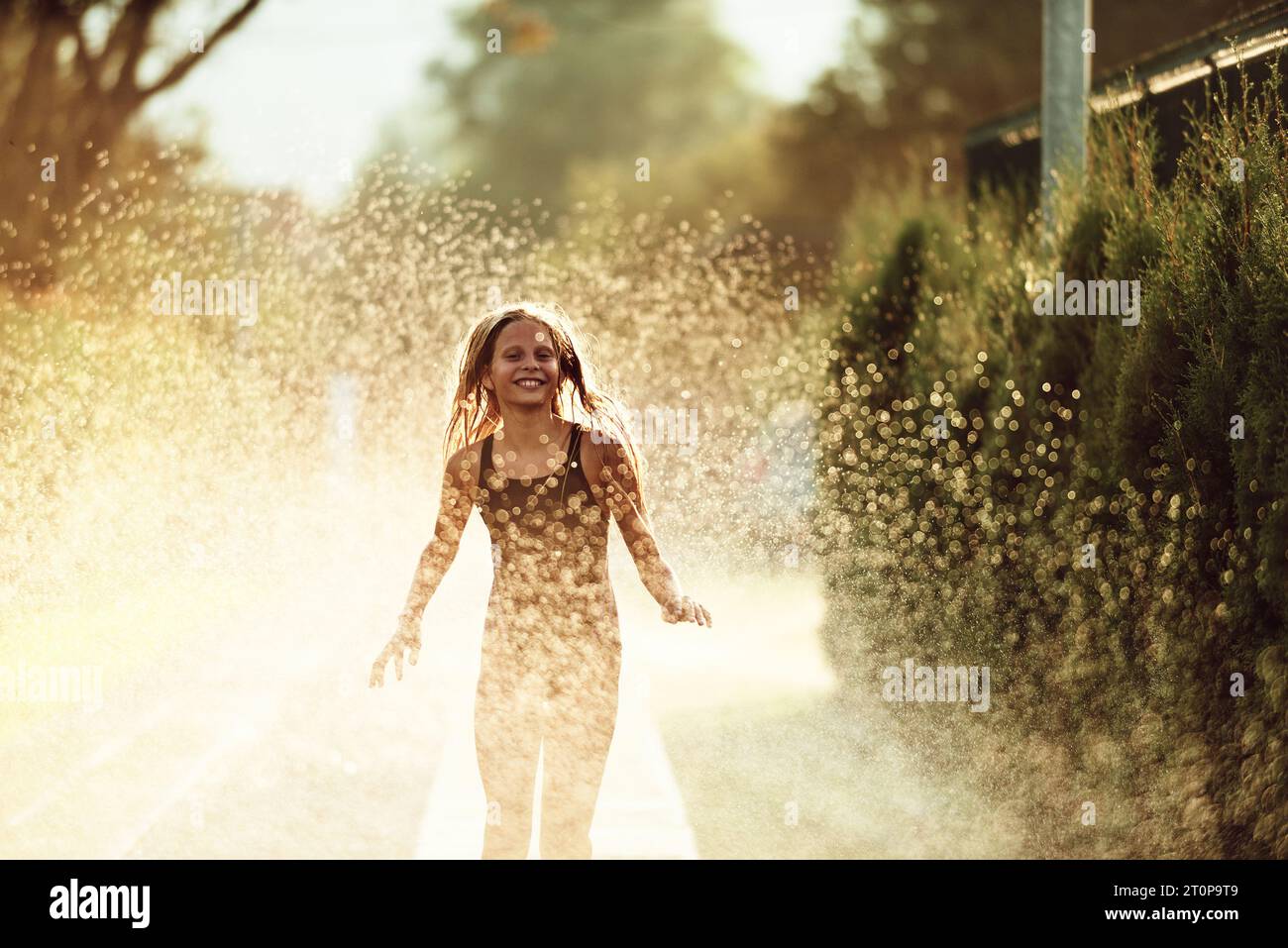 In the backyard of house, a young girl bursts with laughter and joy as she gleefully runs ...