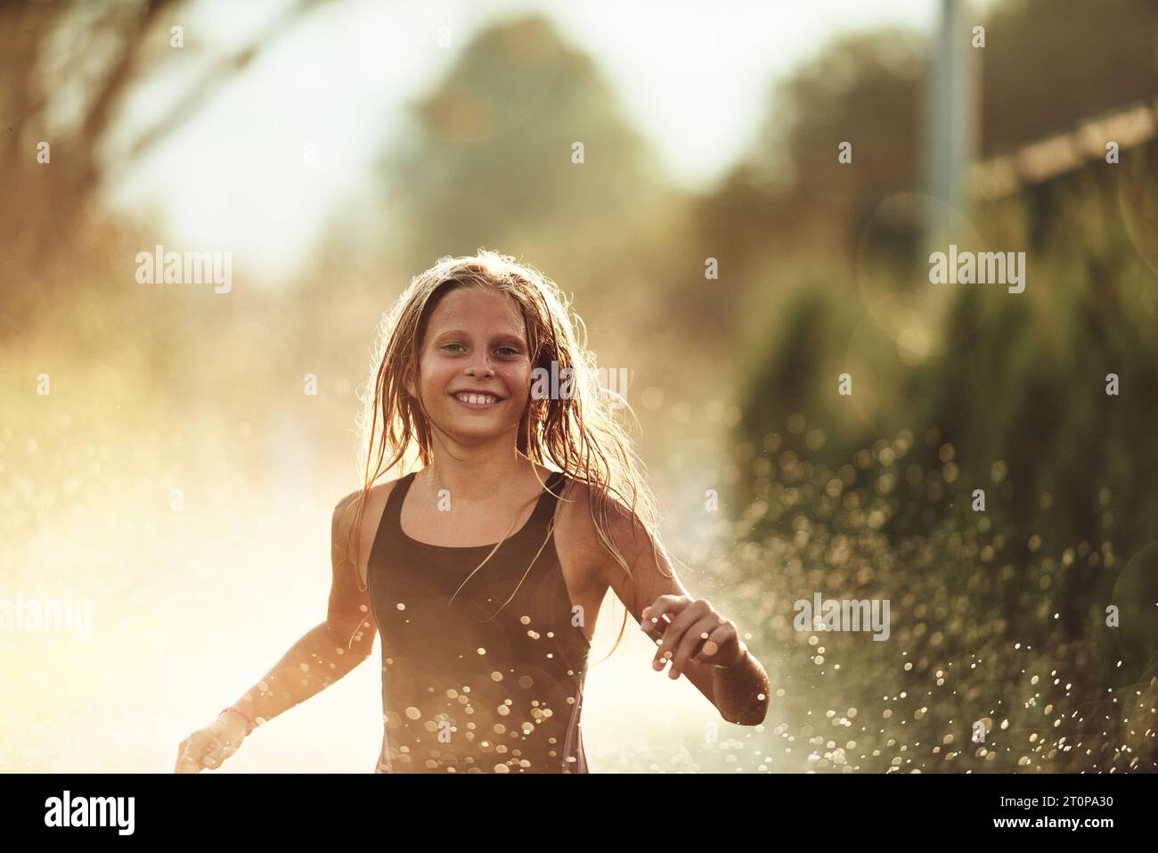 In the backyard of house, a young girl bursts with laughter and joy as she gleefully runs ...