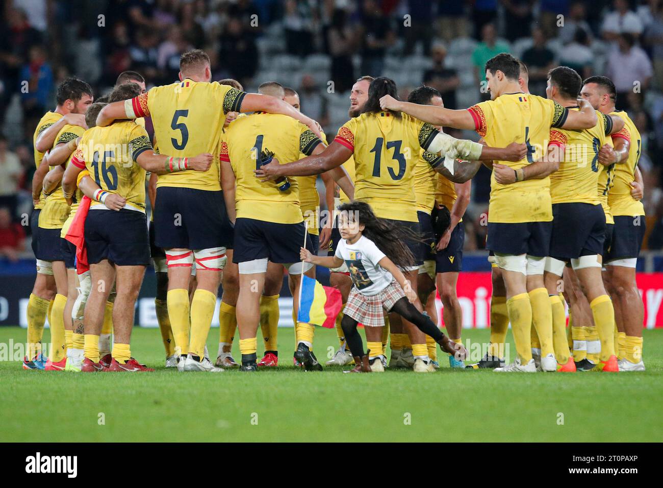 A child plays holding a Romanin flag as Romania's players huddle after ...
