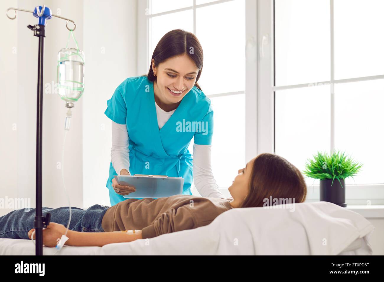 Teenage child girl lying on couch in clinic while receiving IV drip ...