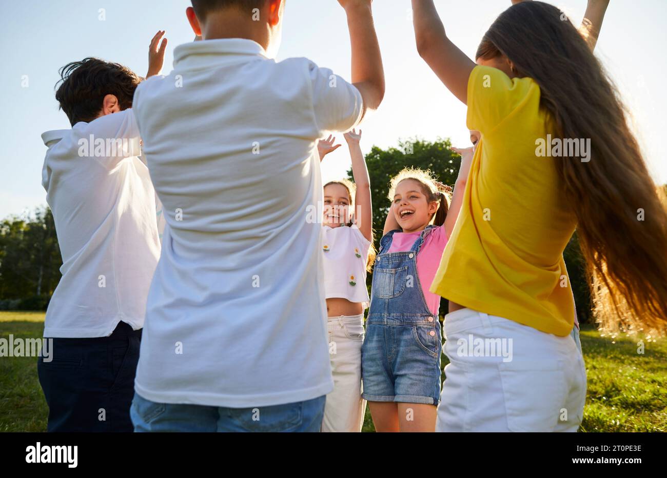 Happy children friends standing together outdoor in summer park raising ...