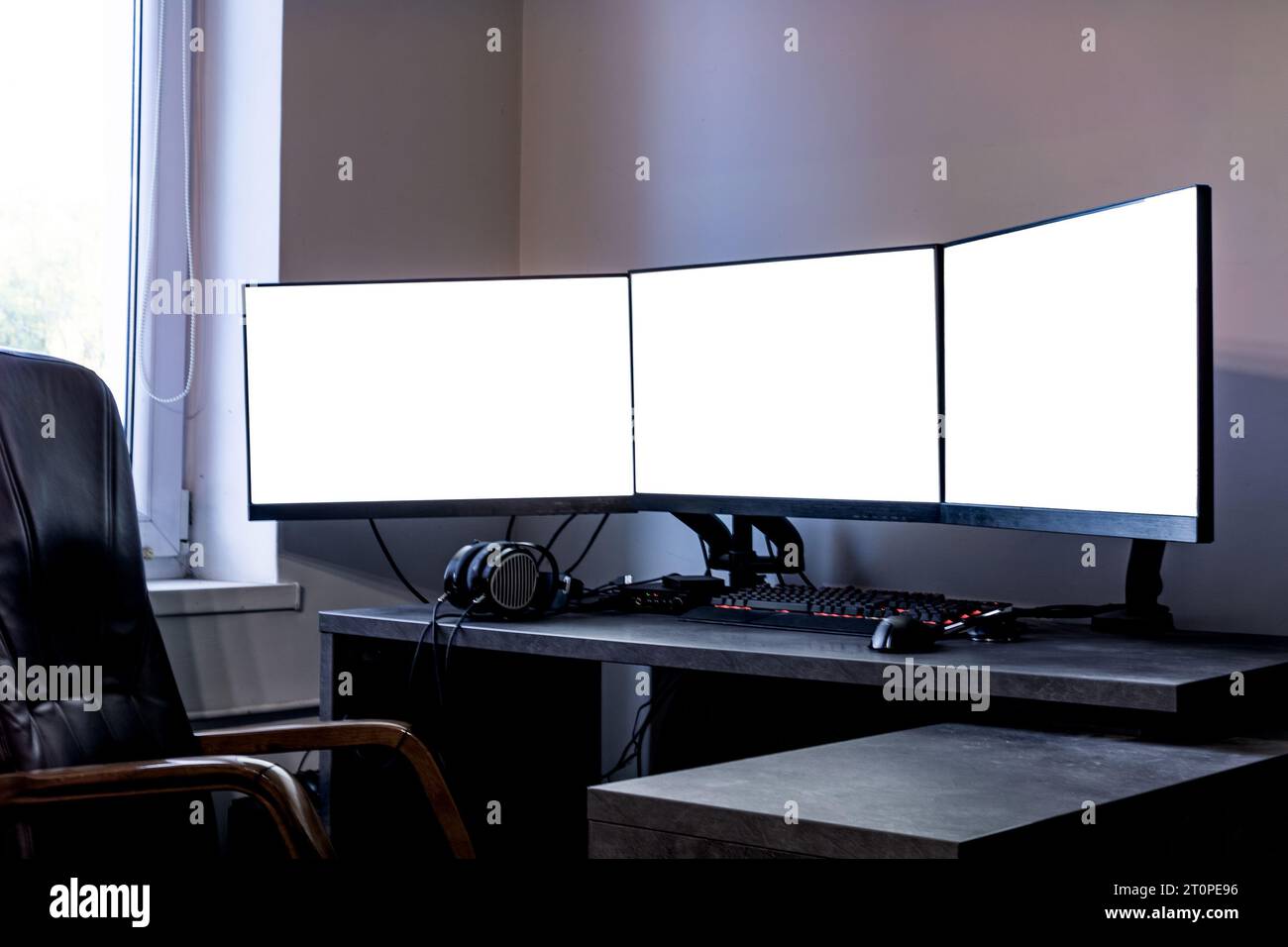 tree empty monitors mock-up on a desk next to a window and a chair ...