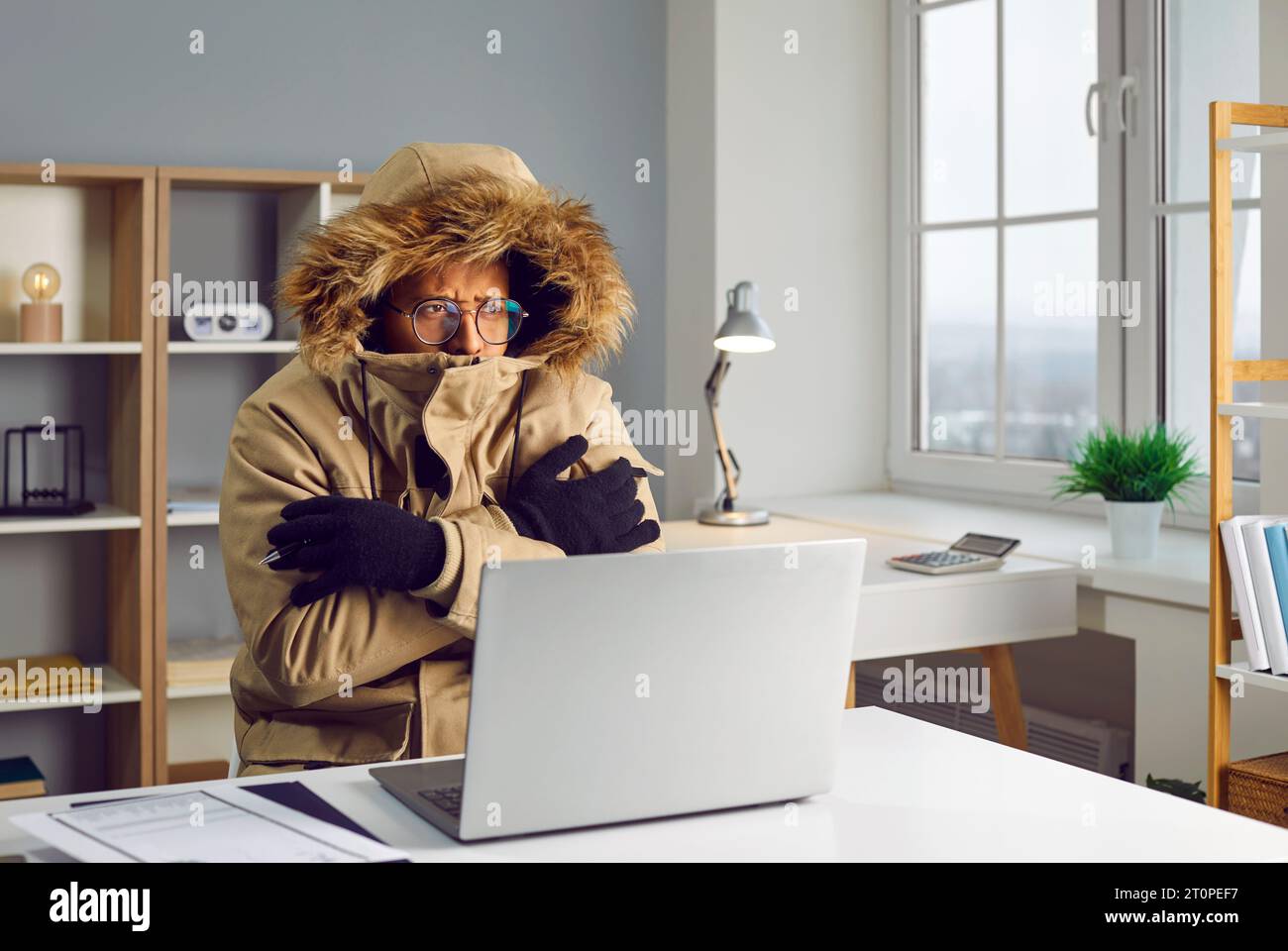 Young african american man working in the cold at home on his laptop ...