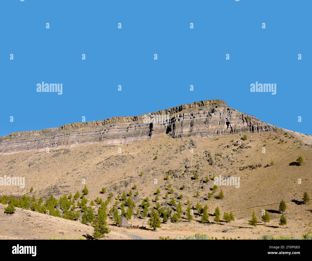 Rocky cliffs sit in the high desert area of Central Oregon. Vivid blue ...