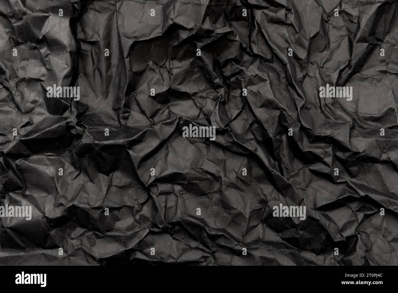 A sheet of black crumpled paper with folds and wrinkles. Dark paper ...