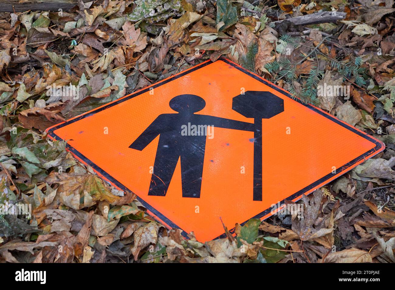 An orange traffic sign with a person holding a stop sign. The sign is ...