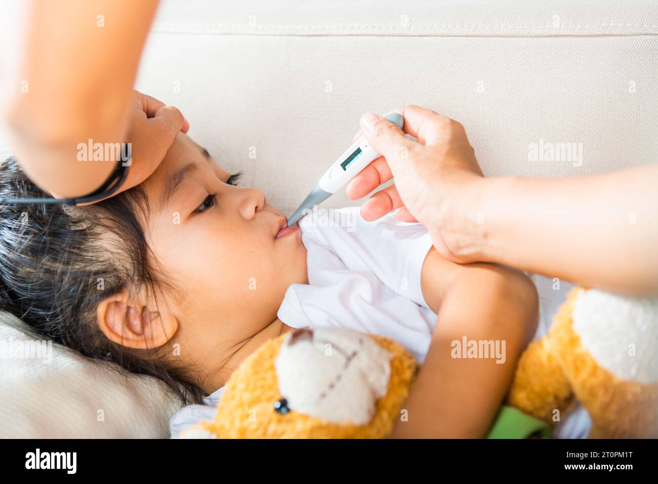 Mother checking temperature of her sick daughter with thermometer in mouth Stock Photo - Alamy