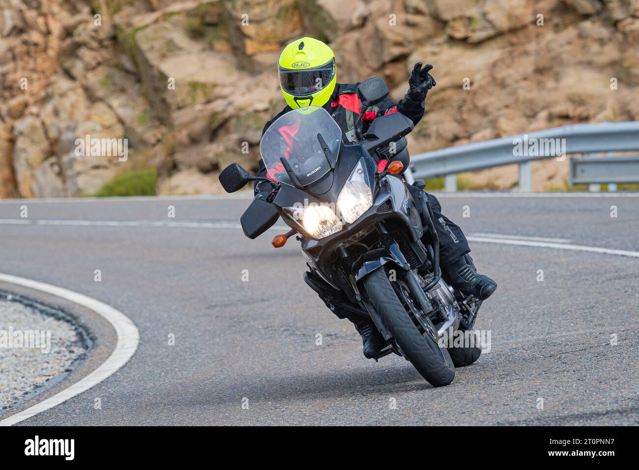 man sitting on his motorcycle, making a sharp turn on the mountain road ...