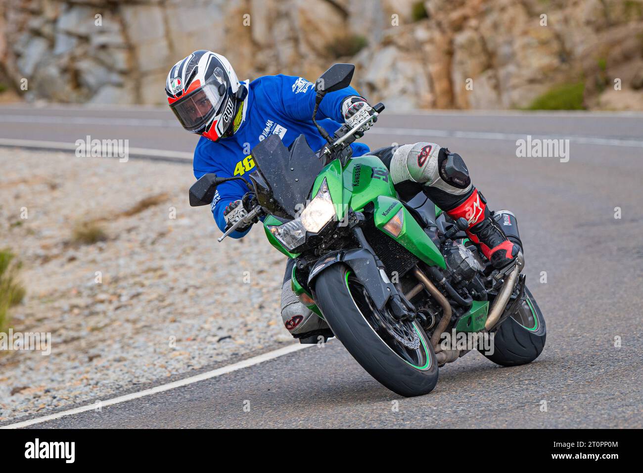 man sitting on his motorcycle, making a sharp turn on the mountain road ...