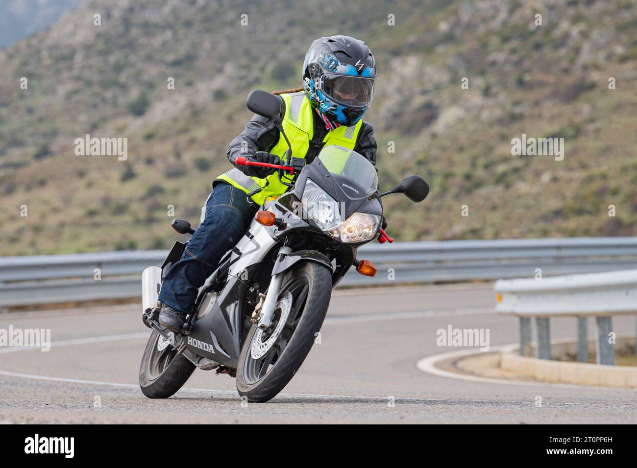 man sitting on his motorcycle, making a sharp turn on the mountain road ...