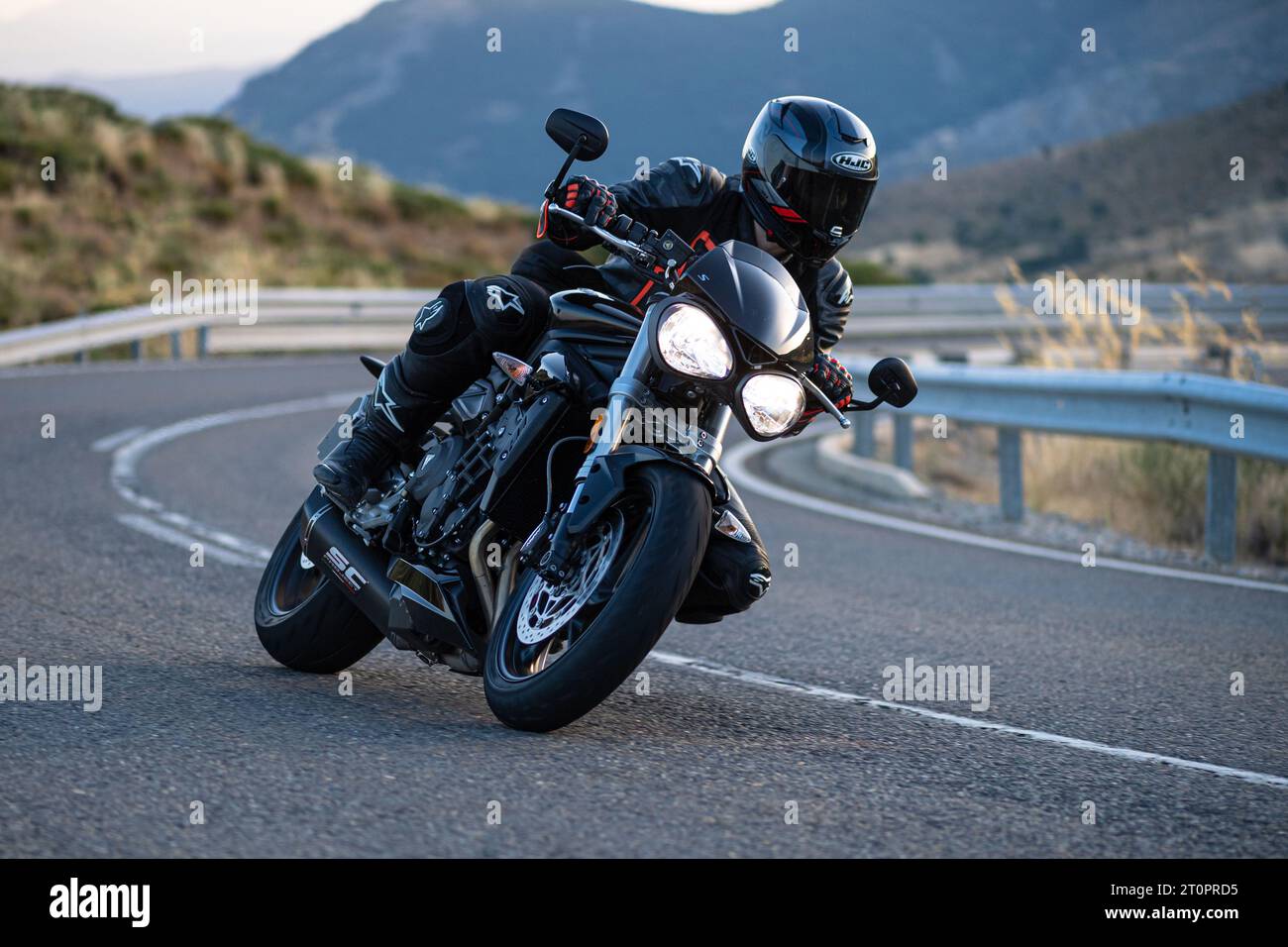 man sitting on his motorcycle, making a sharp turn on the mountain road ...