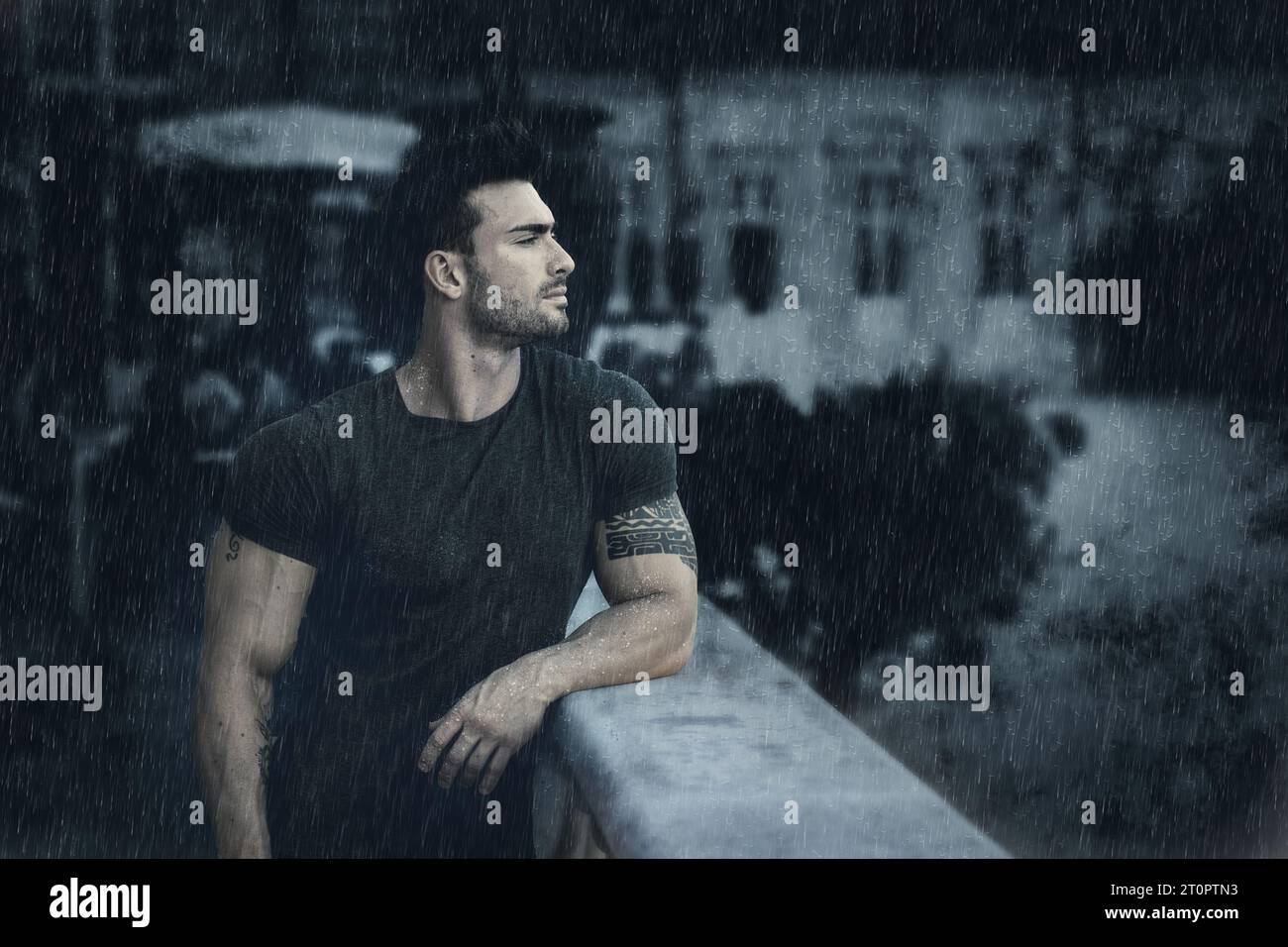 A man leaning on a rail in the rain. Photo of a ruggedly handsome man ...
