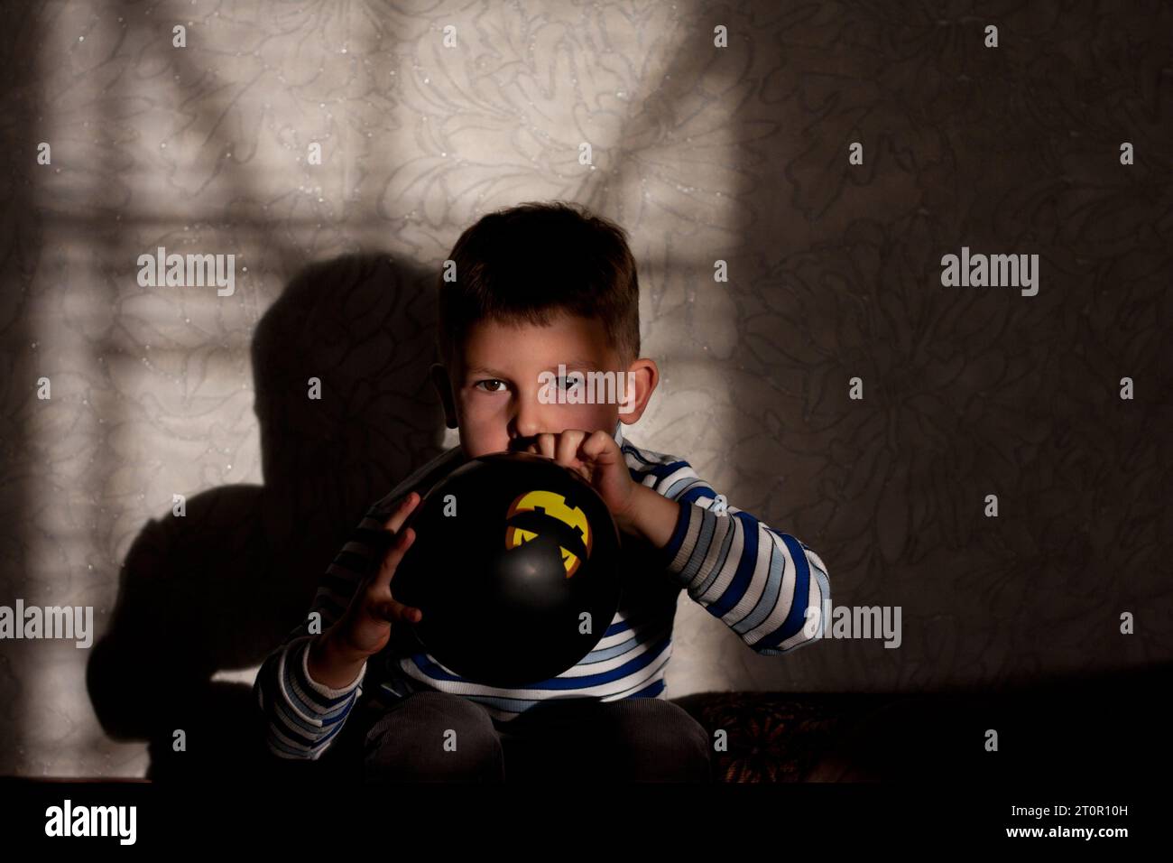 Happy Halloween. child inflating black balloon. Portrait of preschooler ...