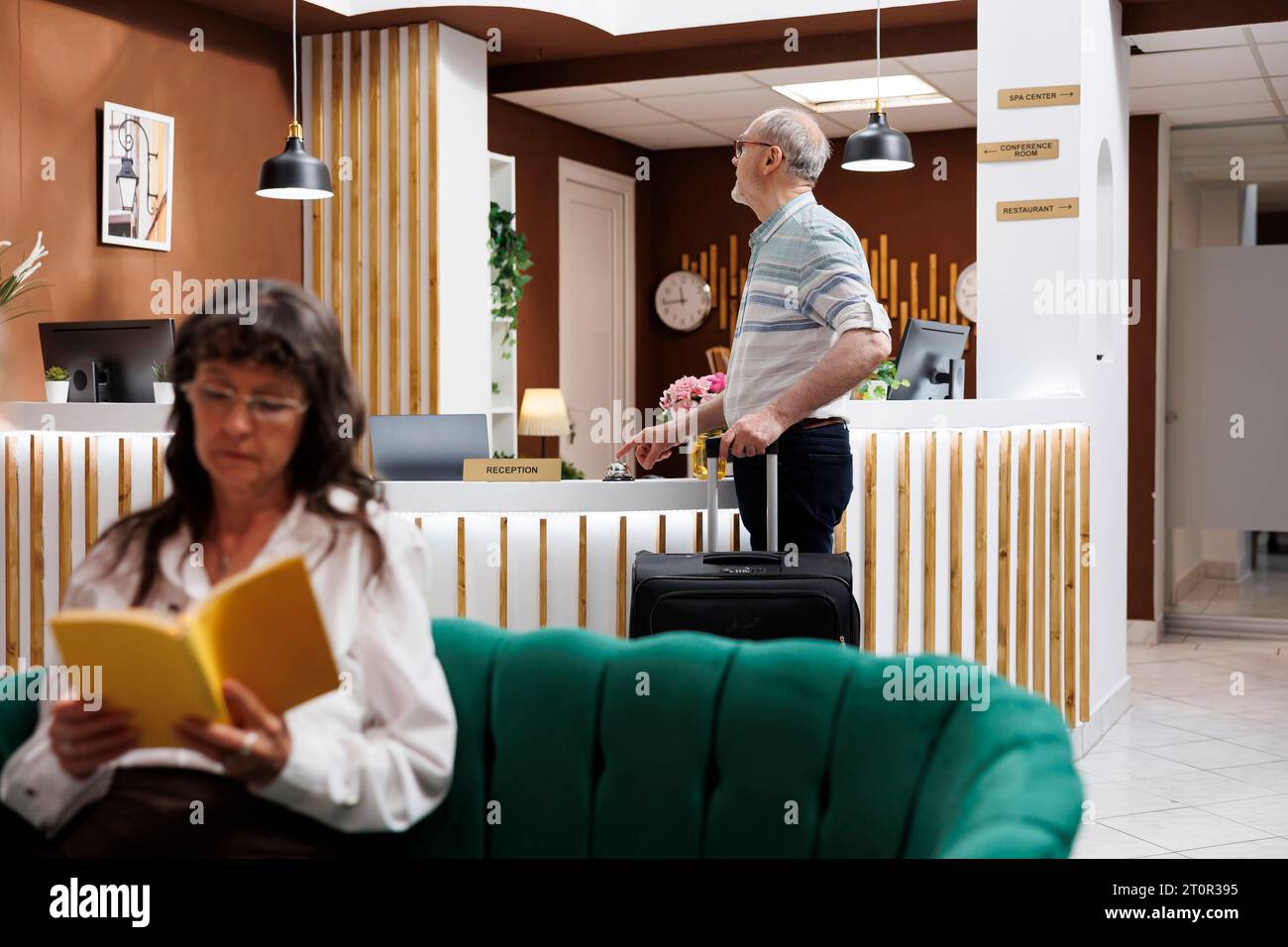 Caucasian elderly man arrives at front desk and rings the silver ...