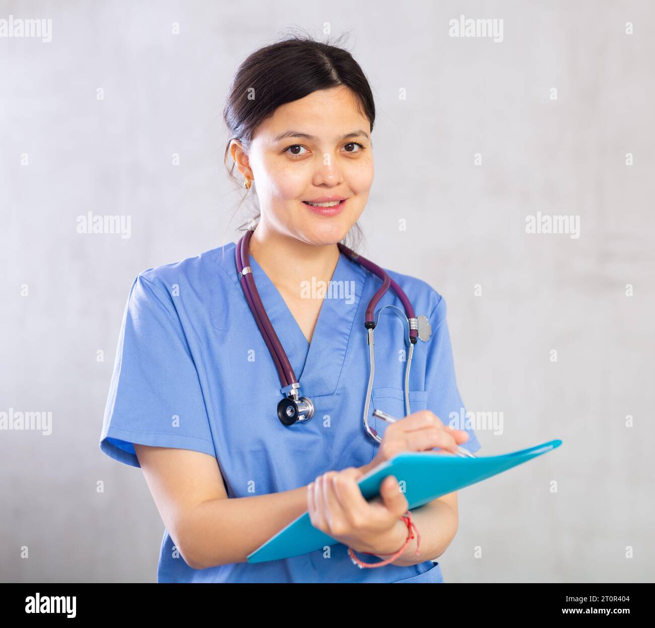 Female doctor in blue uniform filling out medical form Stock Photo - Alamy
