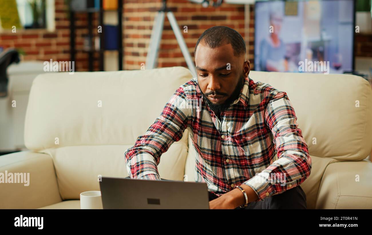 Teleworking employee inputing data on laptop while sitting at home with ...