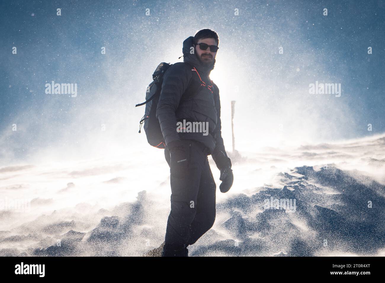 A lone hikers in warm clothes, in the cold winter walks on the frozen mountain, on sunny day ...