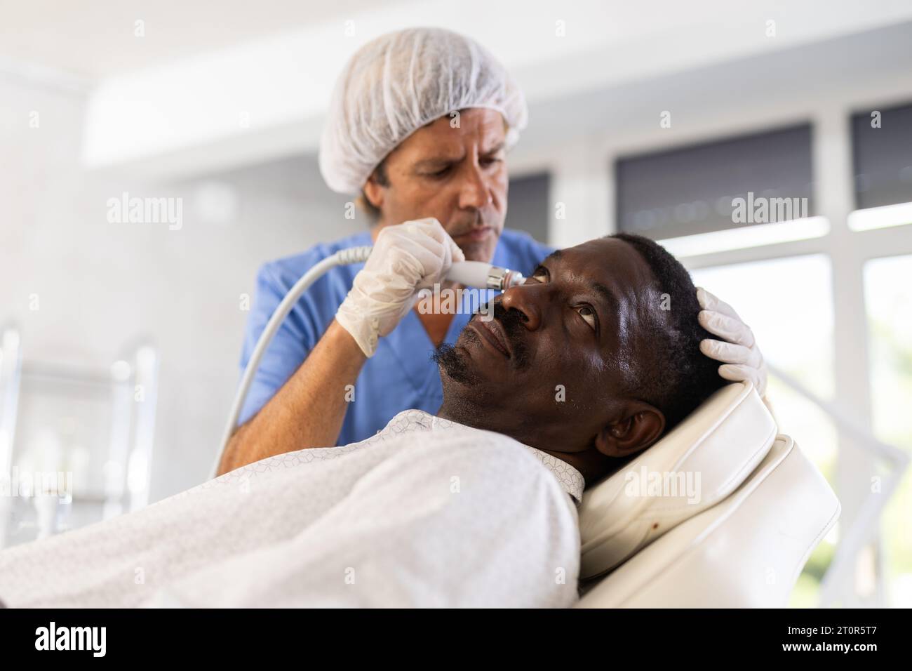 Male cosmetologist performs skin cleansing procedure for African man ...