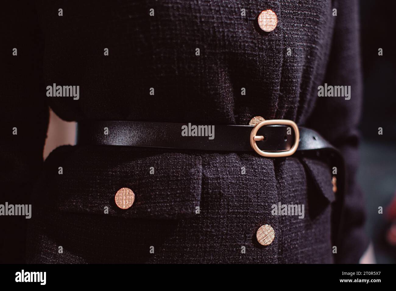 Fashion details of a classy black jacket, leather belt and golden ...