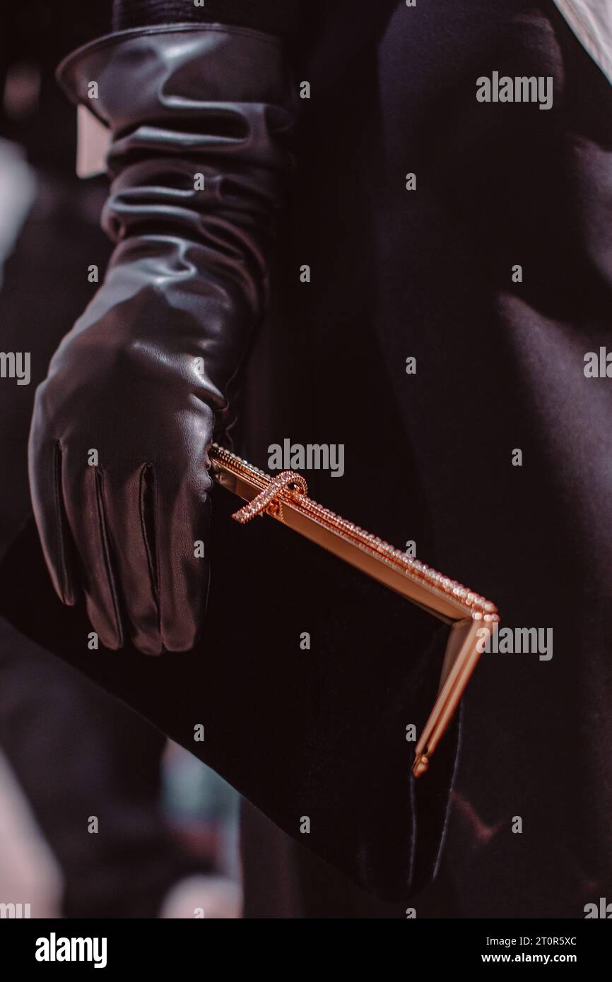 A female hand in a black leather glove holding a classic velvet clutch ...