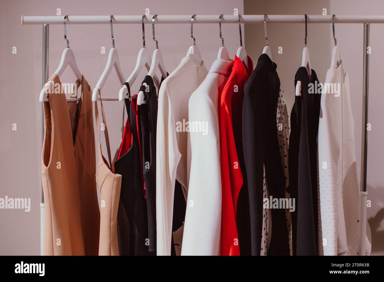 Designer fashion outfits hanging in a row at the backstage. Beige ...