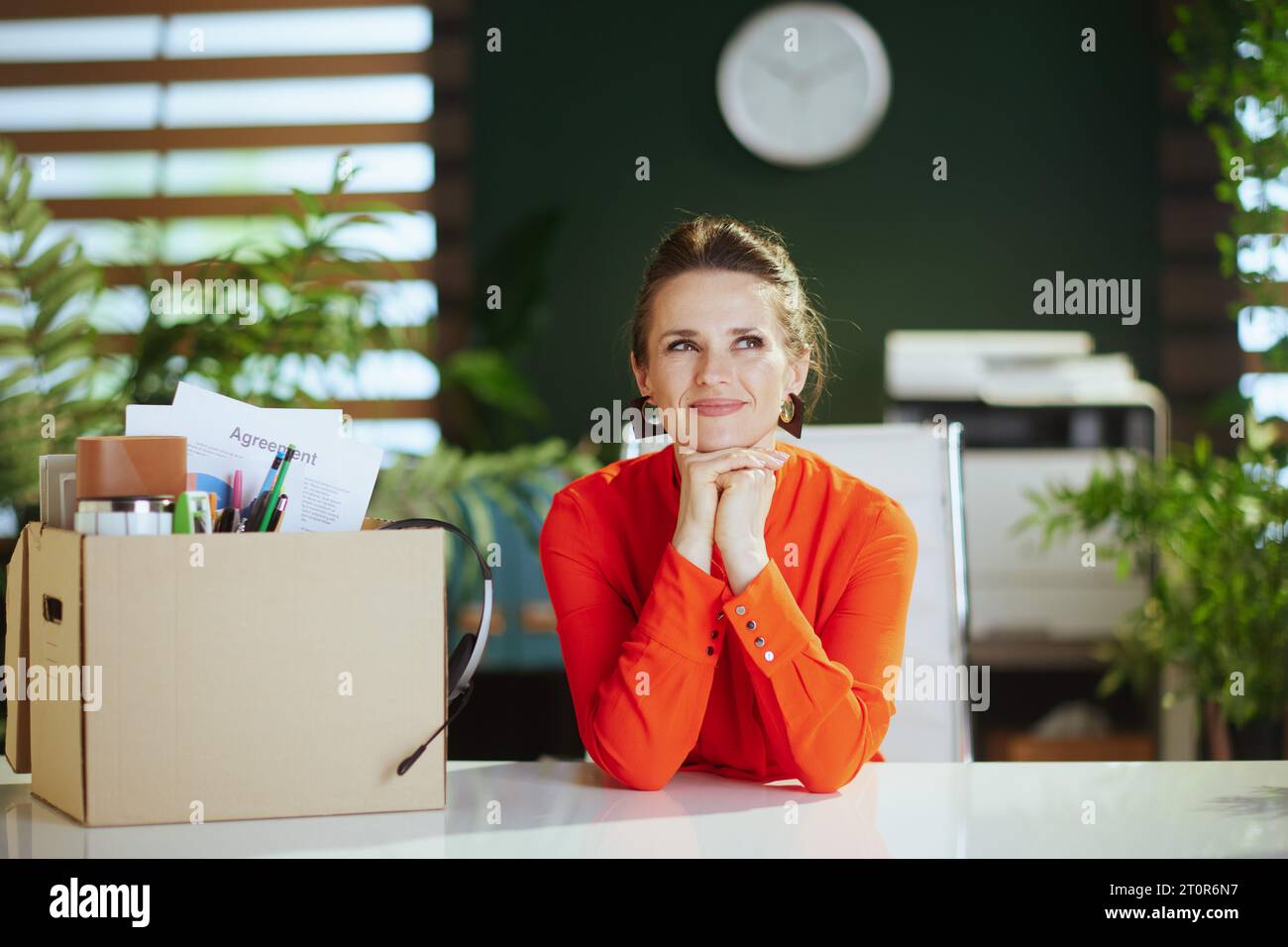 New job. Happy modern woman worker in modern green office in red blouse ...