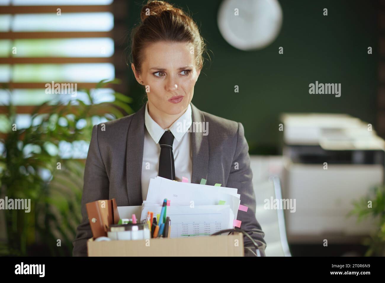 New job. concerned modern woman worker in modern green office in grey ...