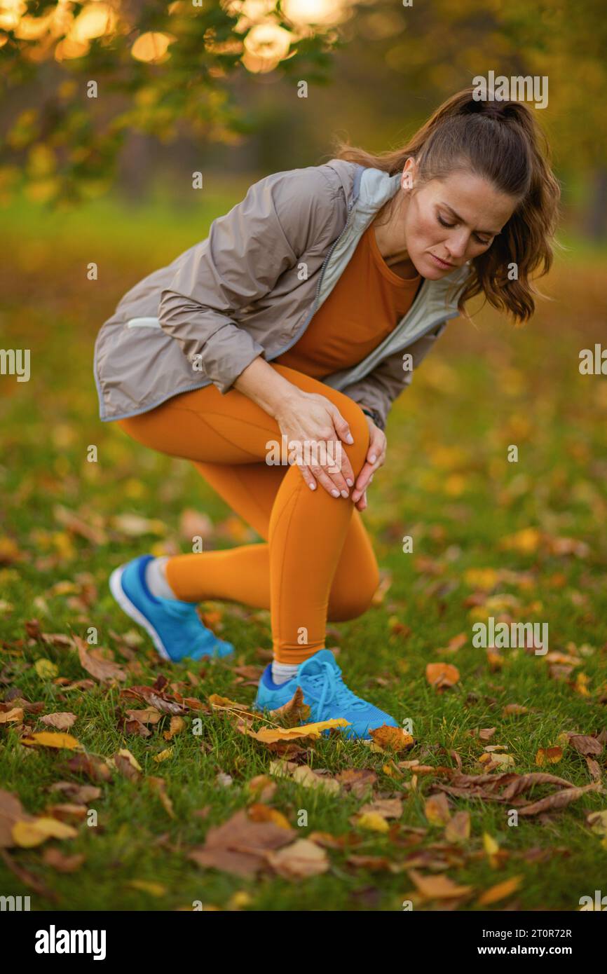 Hello autumn. sad modern woman in fitness clothes in the park got a leg ...