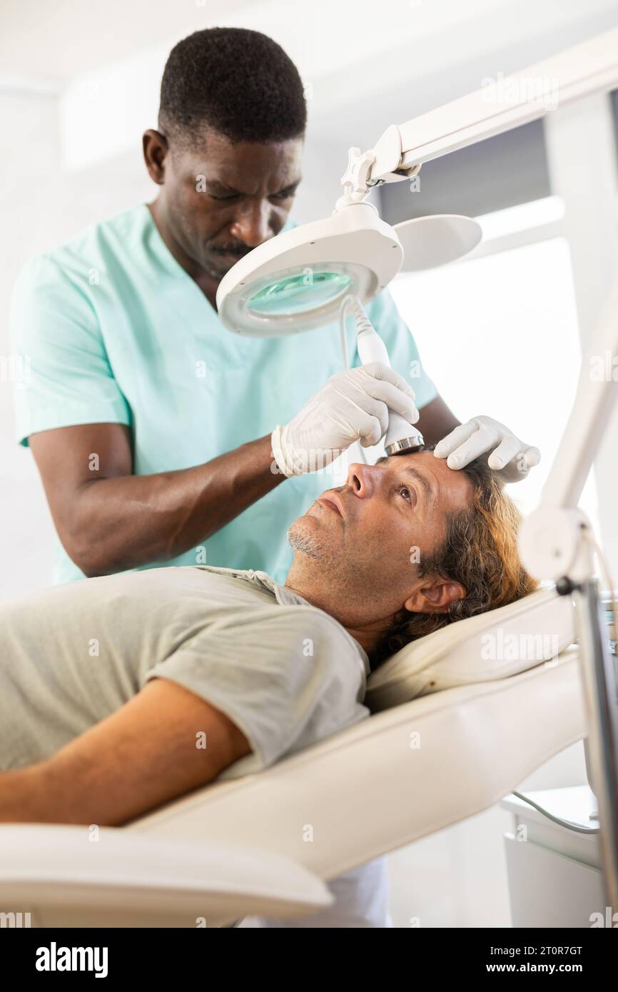 Adult man receiving high frequency ultrasonic facial procedure Stock ...