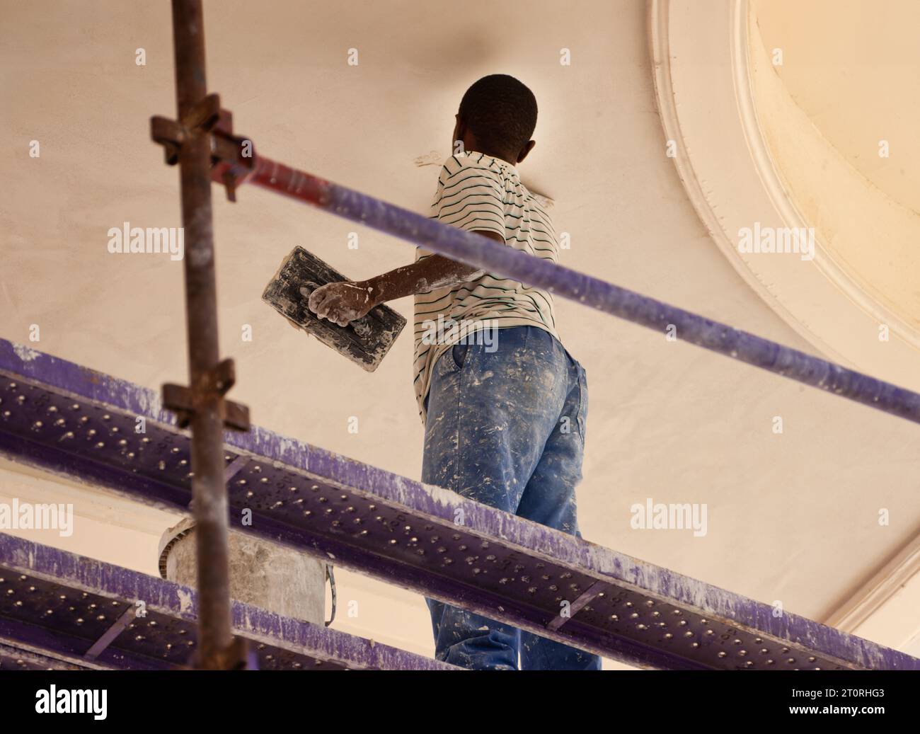 african construction worker climbed on scaffolding plastering a wall ...