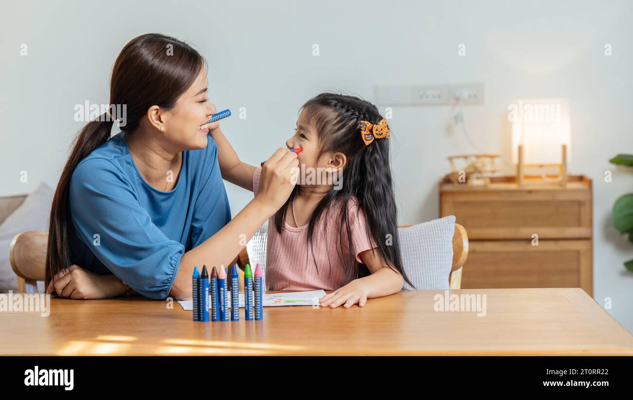 Happy family. Mother and daughter drawing together. Adult woman helping ...