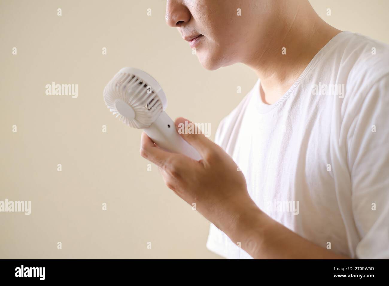 A young Asian man is using a portable fan because of hot weather Stock ...