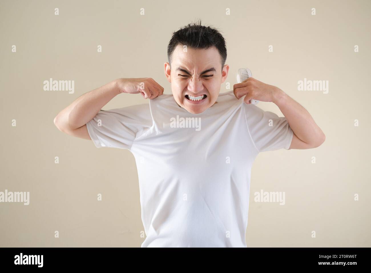 A young Asian man showing his angry expression while holding portable ...