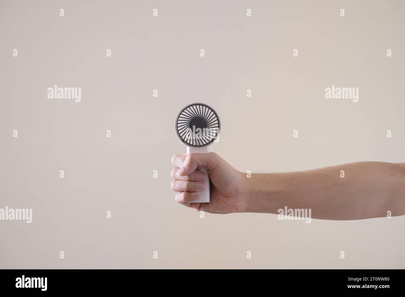 Handheld portable mini fan on isolated beige background Stock Photo - Alamy