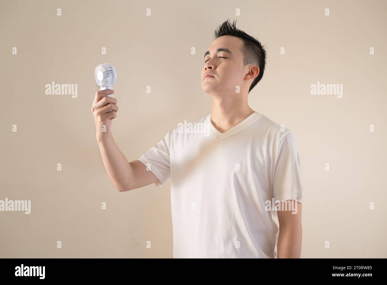 A young Asian man is using a portable fan because of hot weather Stock ...
