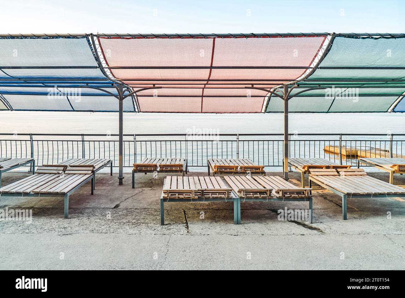 Wooden sun beds in recreational area of sea beach under transparent ...
