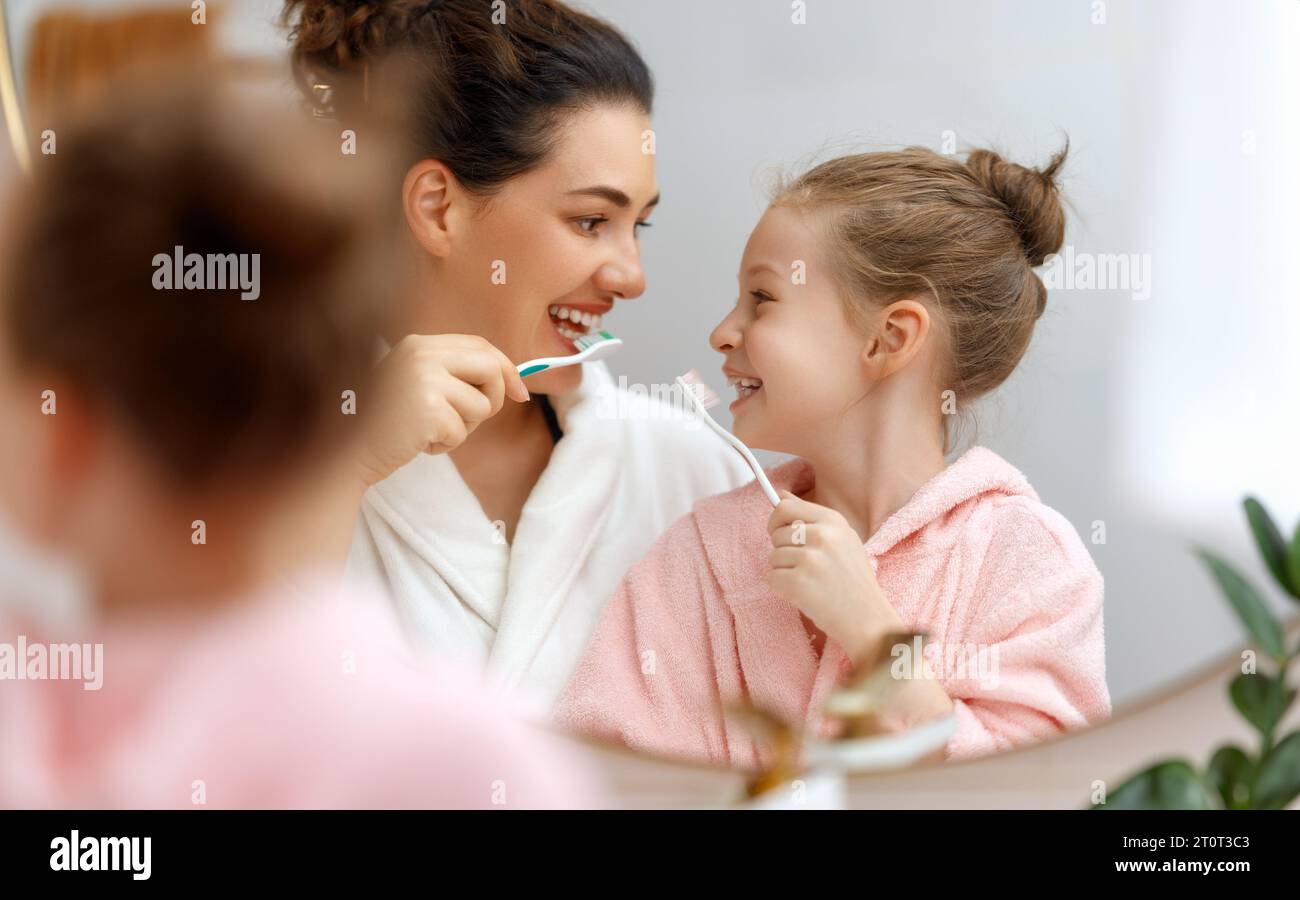 Happy family! Mother and daughter child girl are brushing teeth ...