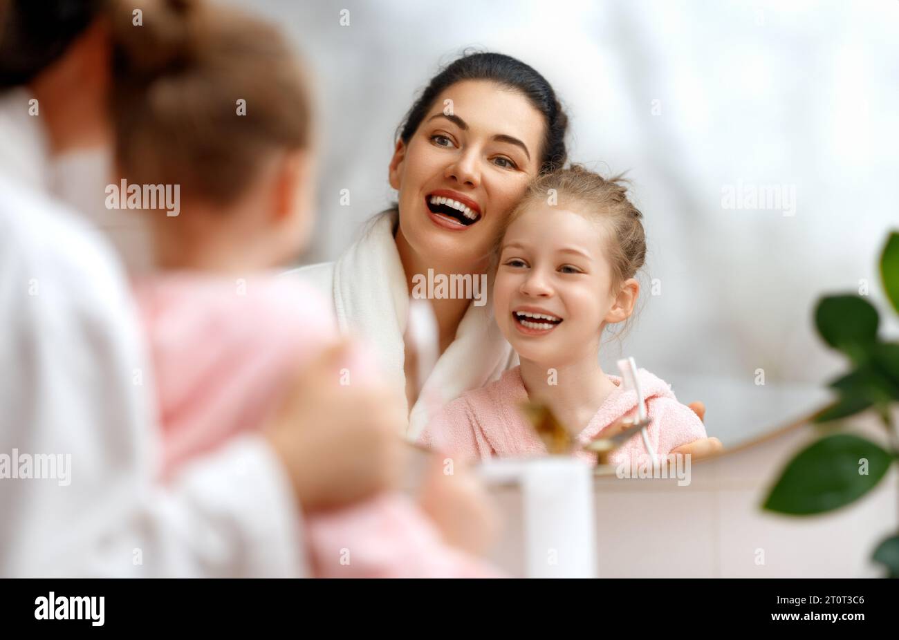 Happy family! Mother and daughter child girl are brushing teeth ...
