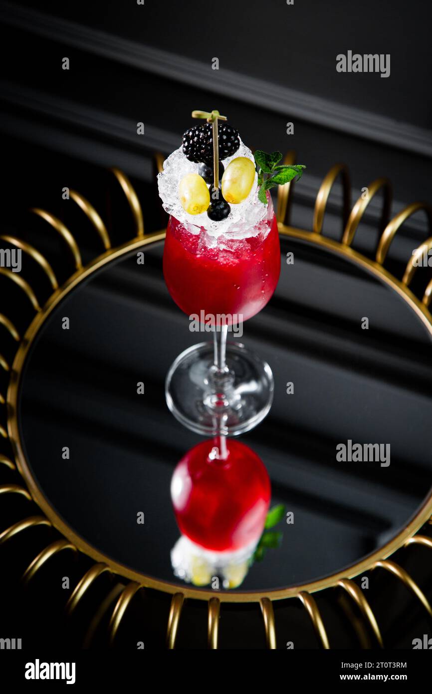 red cocktail on a dark background with whipped cream topping side view ...