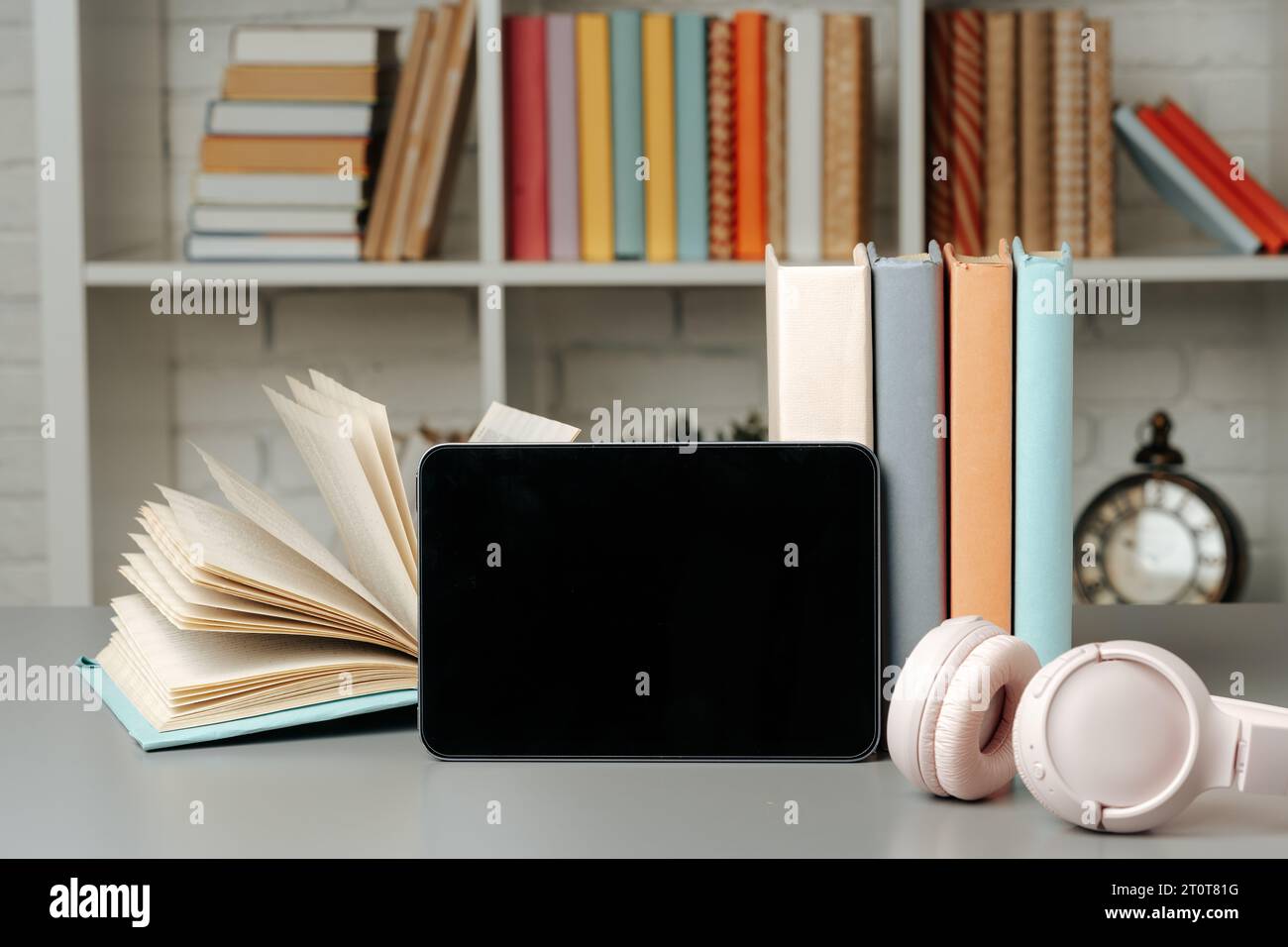 Digital tablet with stacked books in library Stock Photo - Alamy