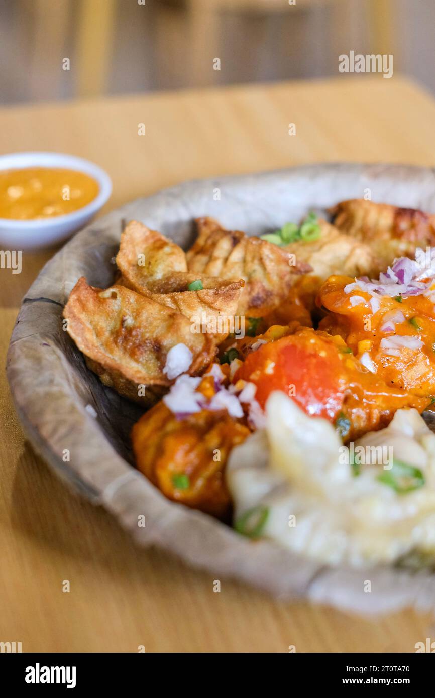 A plate of assorted chicken momos (steamed, fried and chilli sauce ...