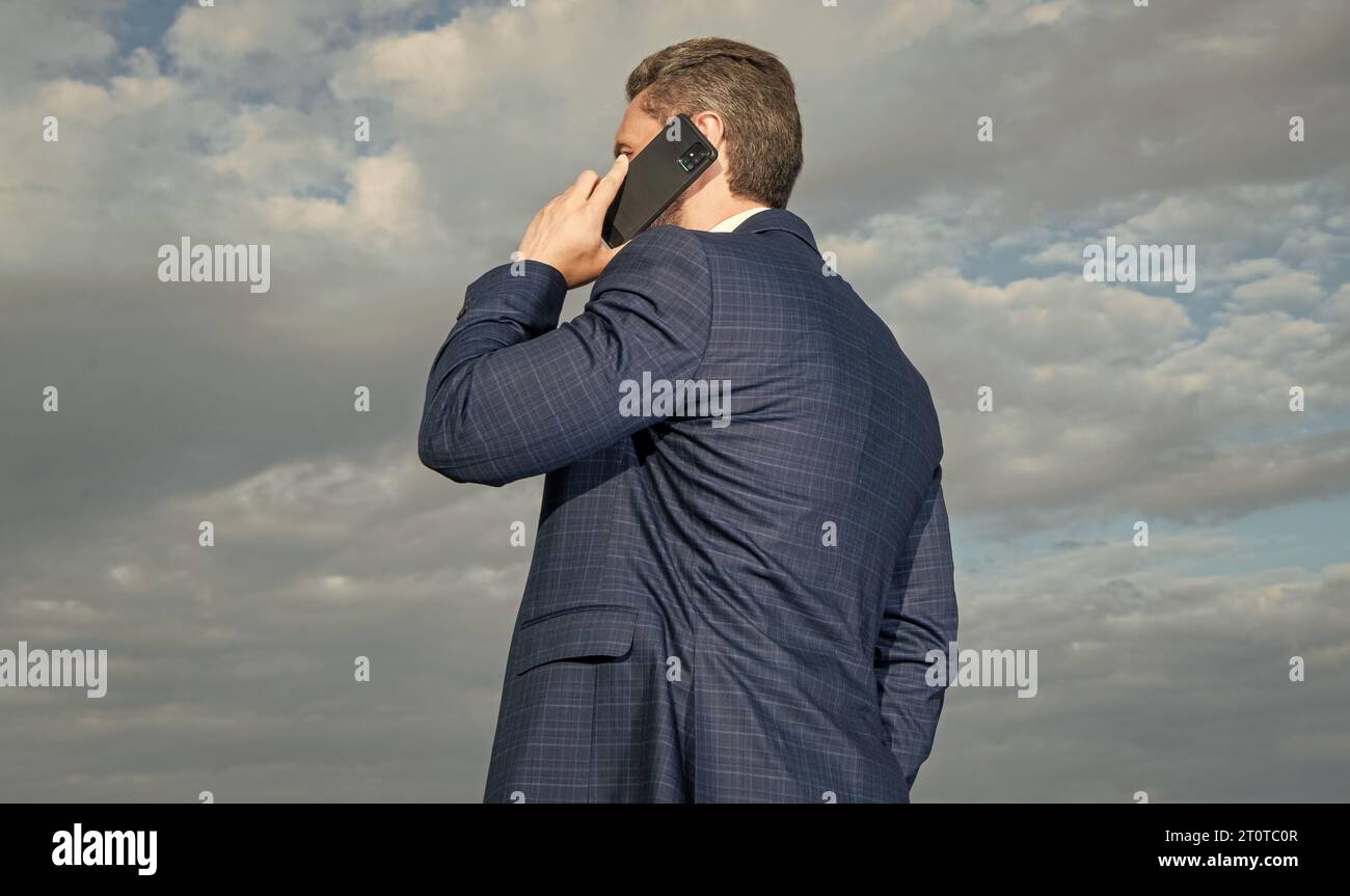 back view photo of man having phone talk. man has phone talk on sky ...